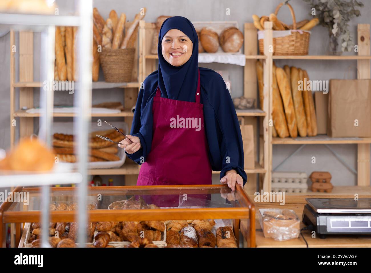 Asian Muslim woman bakery worker sells croissants, stand at counter and ...