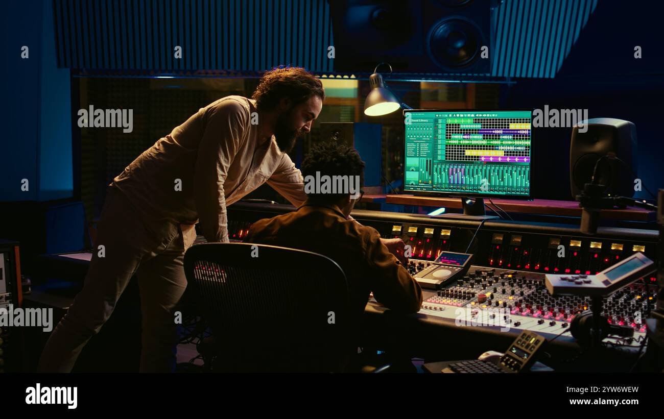 Tracking engineer collaborating with musician to edit sounds in studio ...
