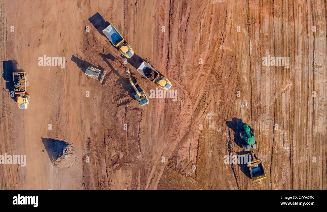 An aerial view of a bustling construction site shows bulldozers, trucks ...