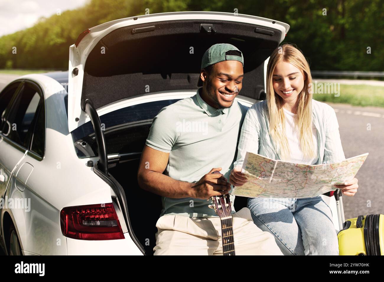 Multiracial couple going on road trip in car, looking at map, taking ...