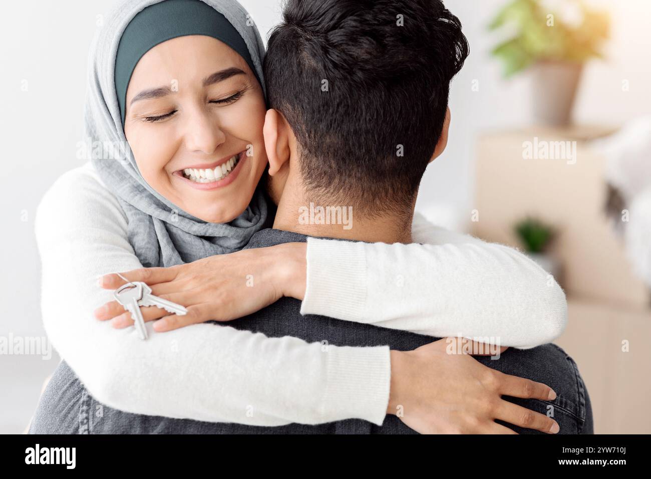 Happy lady in hijab with keychain hugging her husband Stock Photo - Alamy