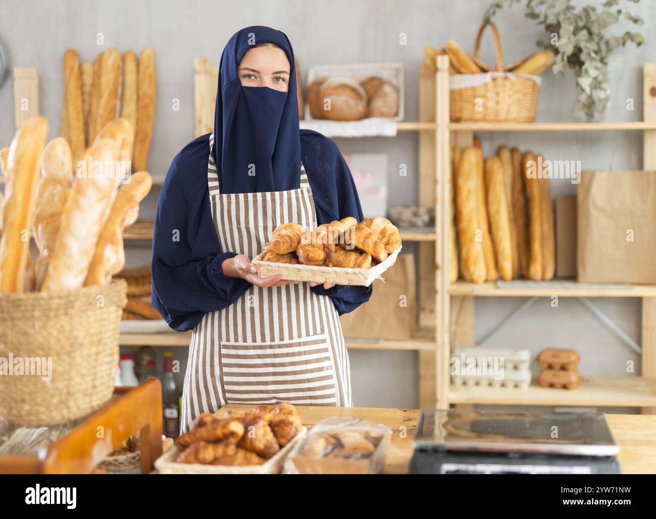 Hospitable saleswoman presenting traditional pastries in Muslim bakery ...
