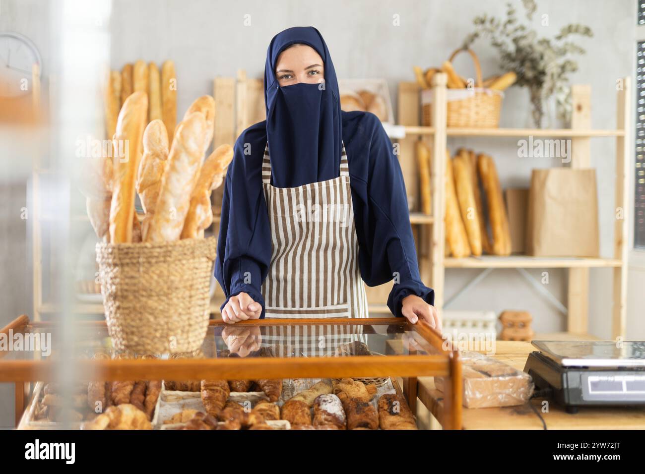 Muslim woman in apron behind pastry counter Stock Photo - Alamy
