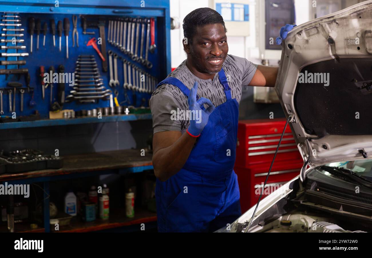 Professional american mechanic man in uniform repairing car engine ...
