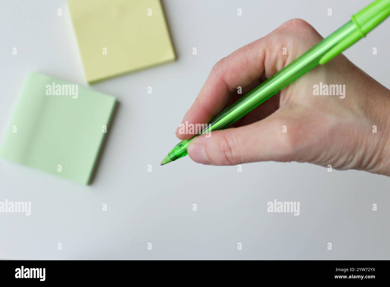 Green ballpoint pen being held by a caucasian human hand, pastel color ...