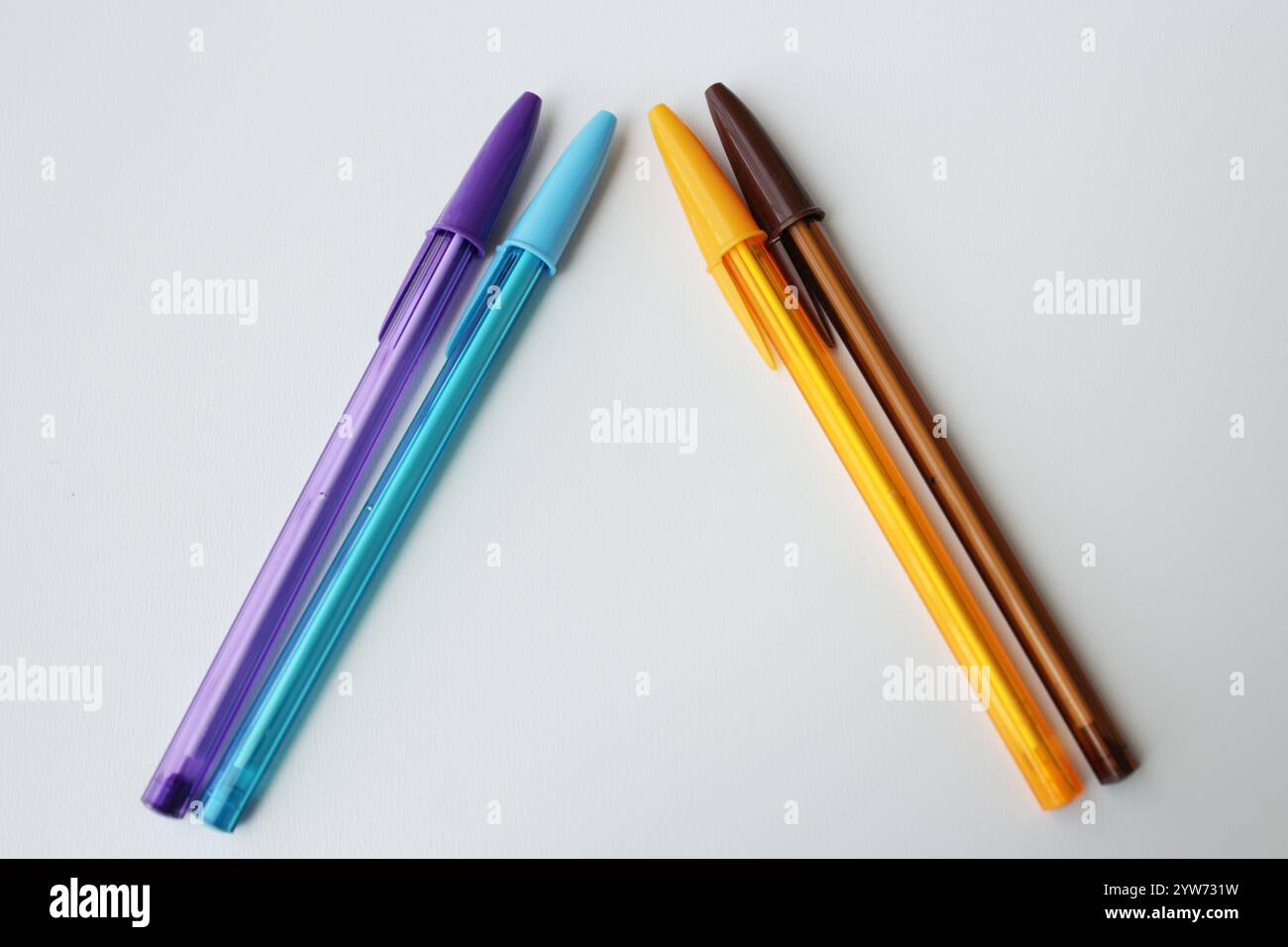 Colorful ballpoint pens arranged in triangular shape on white ...