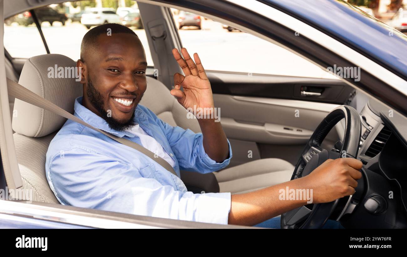 Happy black man sitting in car showing okay gesture Stock Photo - Alamy