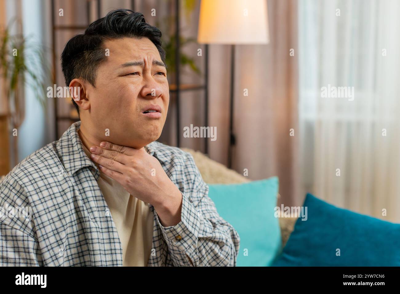 Upset Chinese man holds hands over sore throat. Painful neck and ...