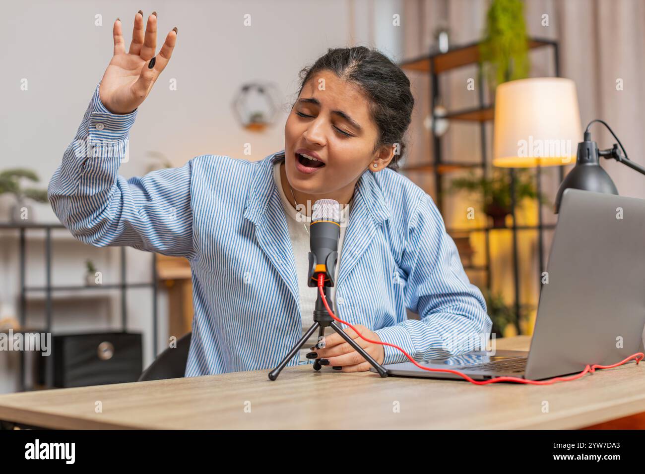 Young positive Indian woman blogger singer using laptop computer while ...