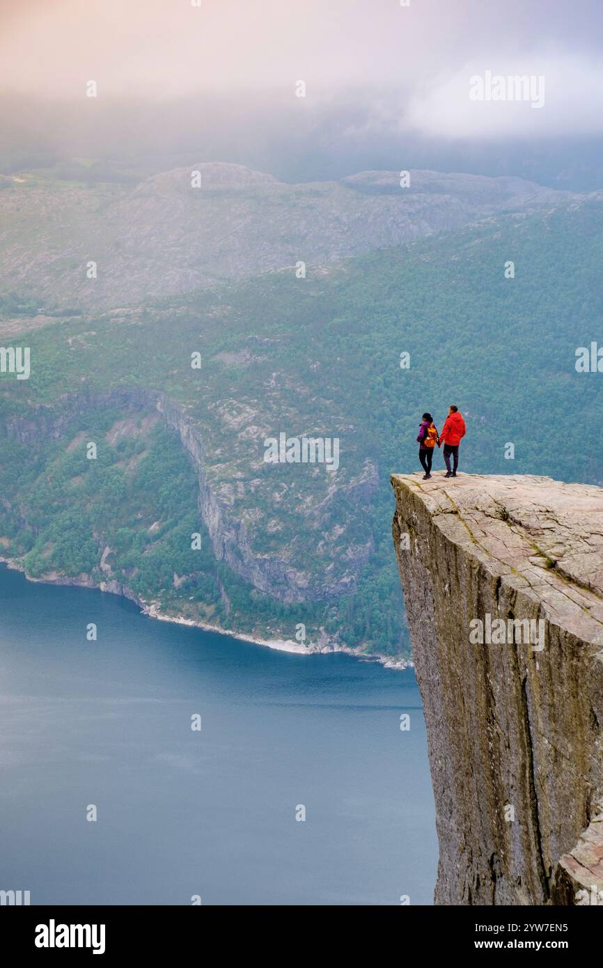 a couple of men and women stand on the edge of a cliff with arms ...