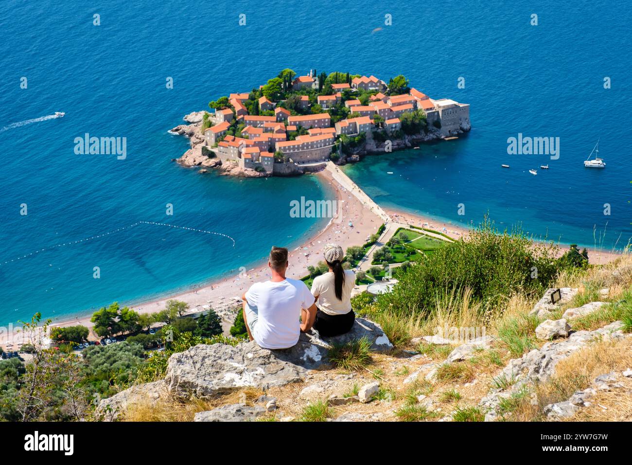 From a scenic vantage point, a couple sits on a rocky ledge, admiring ...