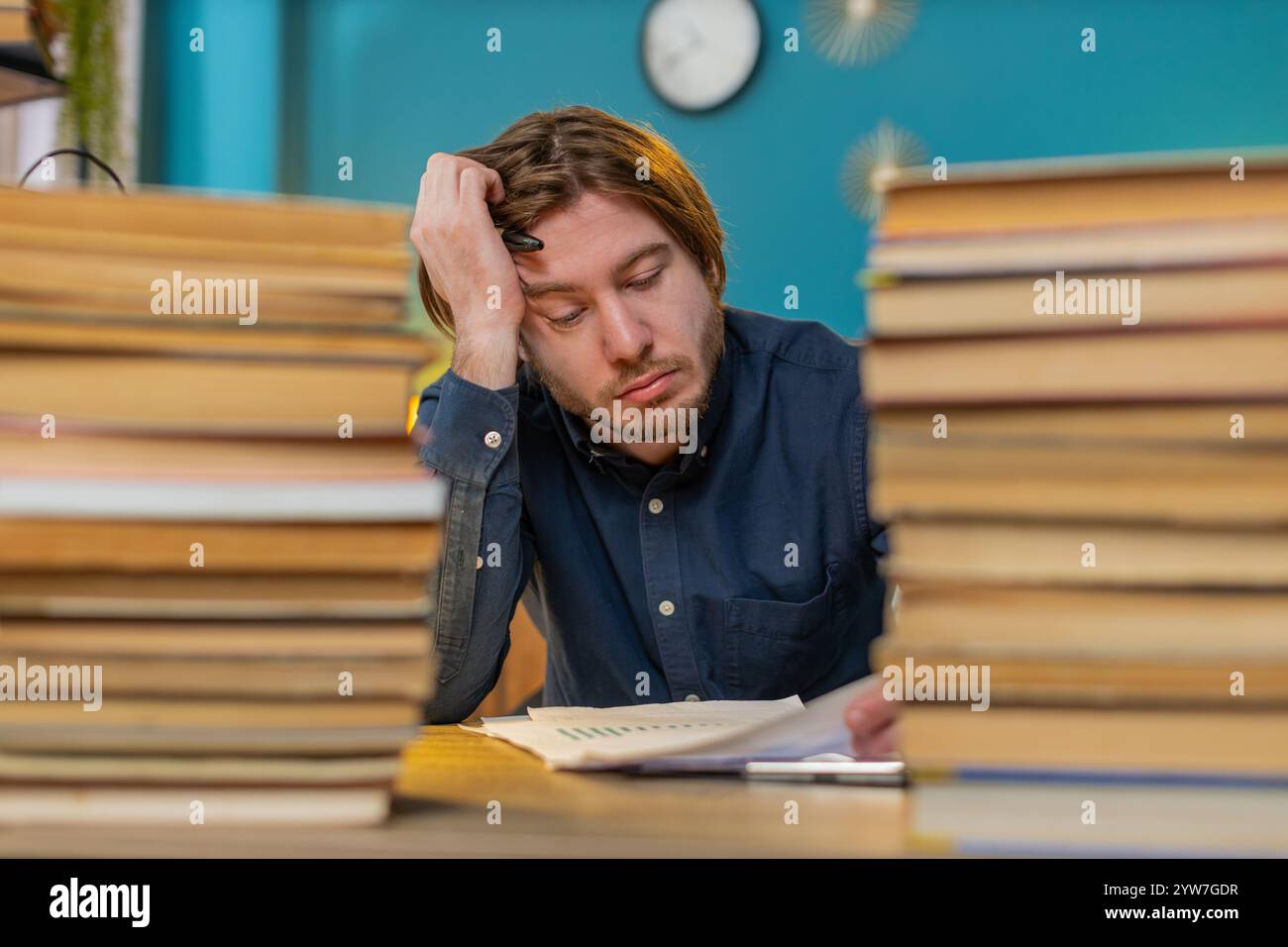 Exhausted Caucasian businessman moving stacks of books and reviewing ...