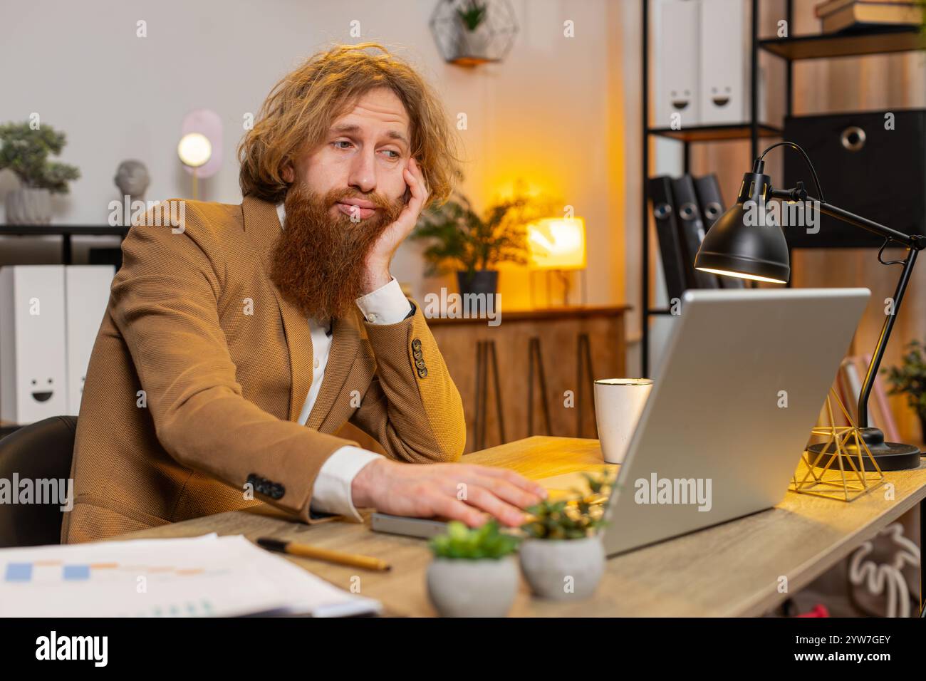 Bored sleepy bearded businessman worker working on laptop computer ...