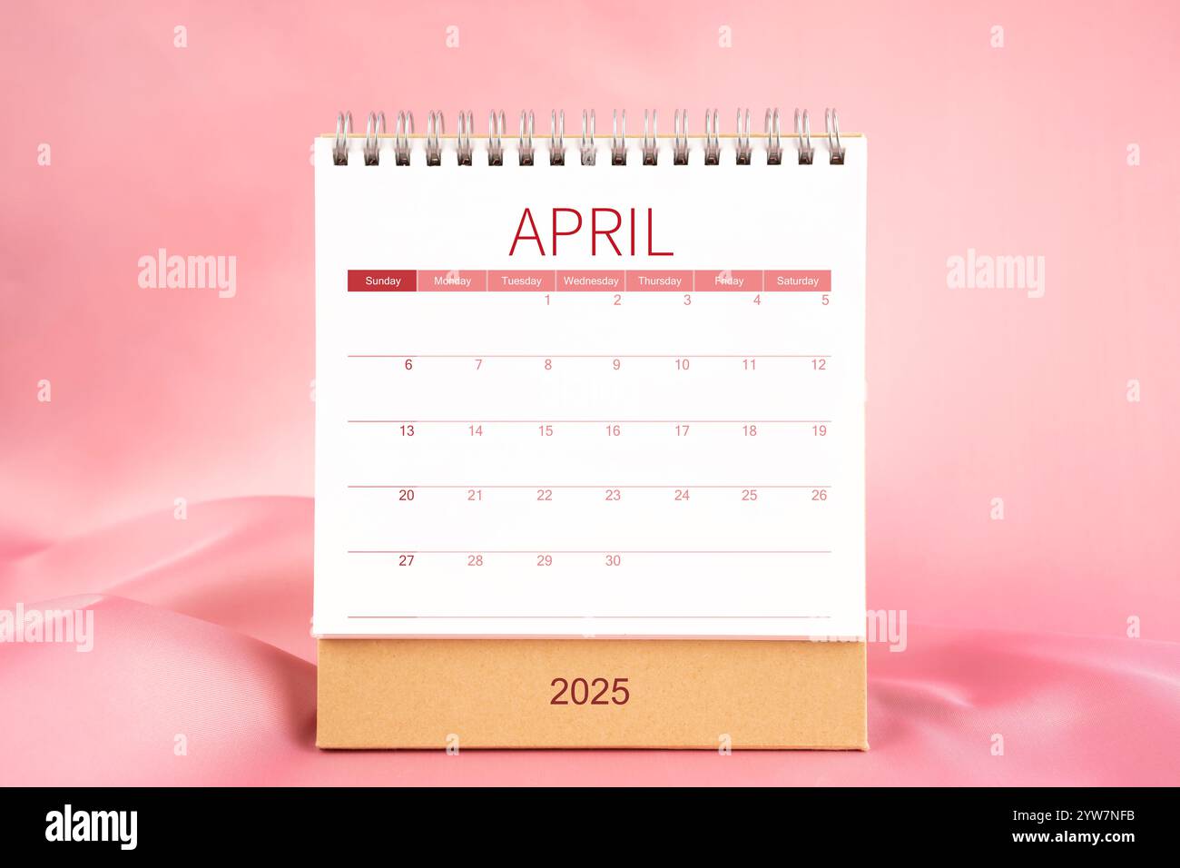 Front view of blank April 2025 desk calendar on pink color textile ...