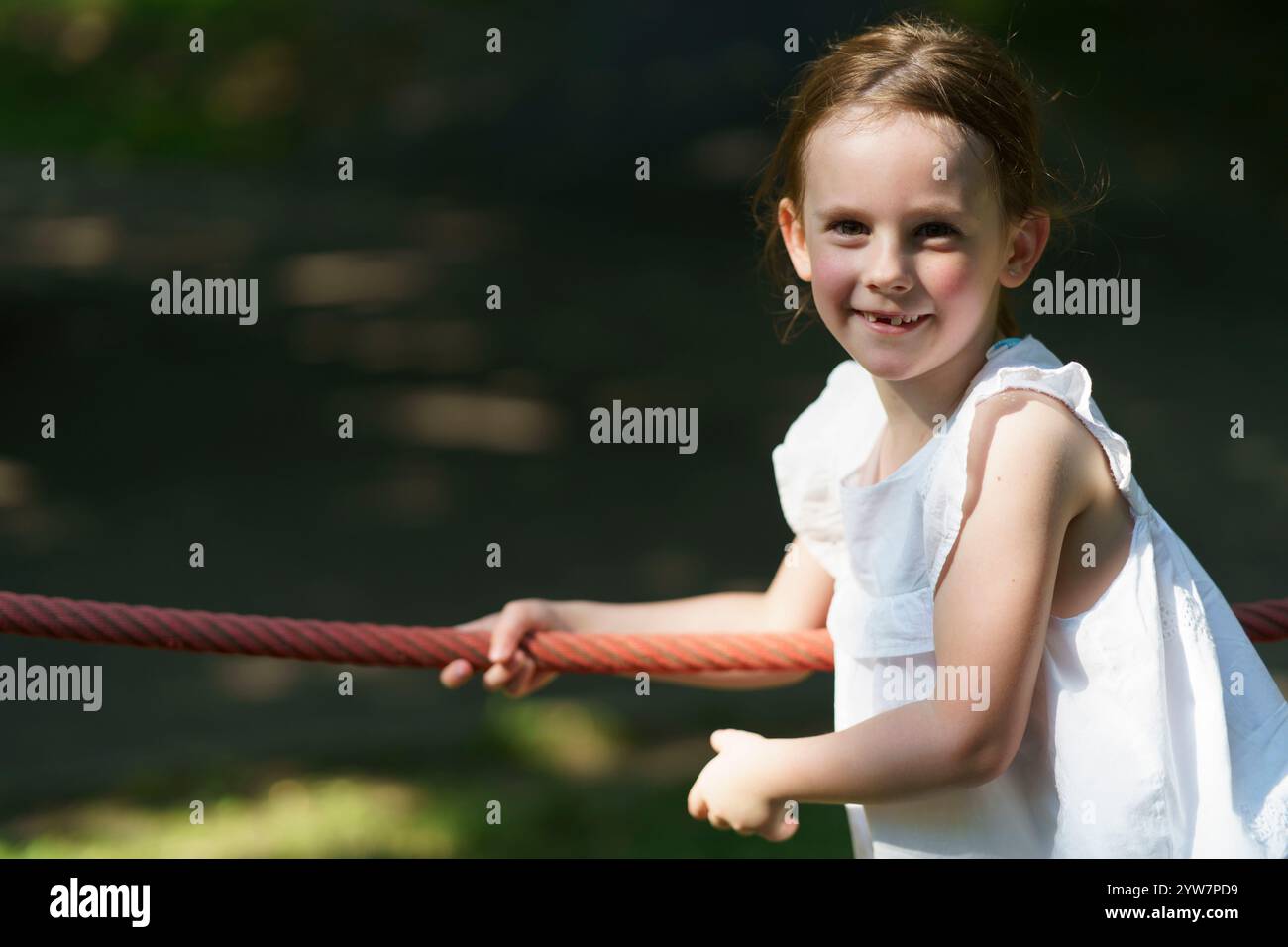 Little cute girl without front tooth rope playground summer park ...
