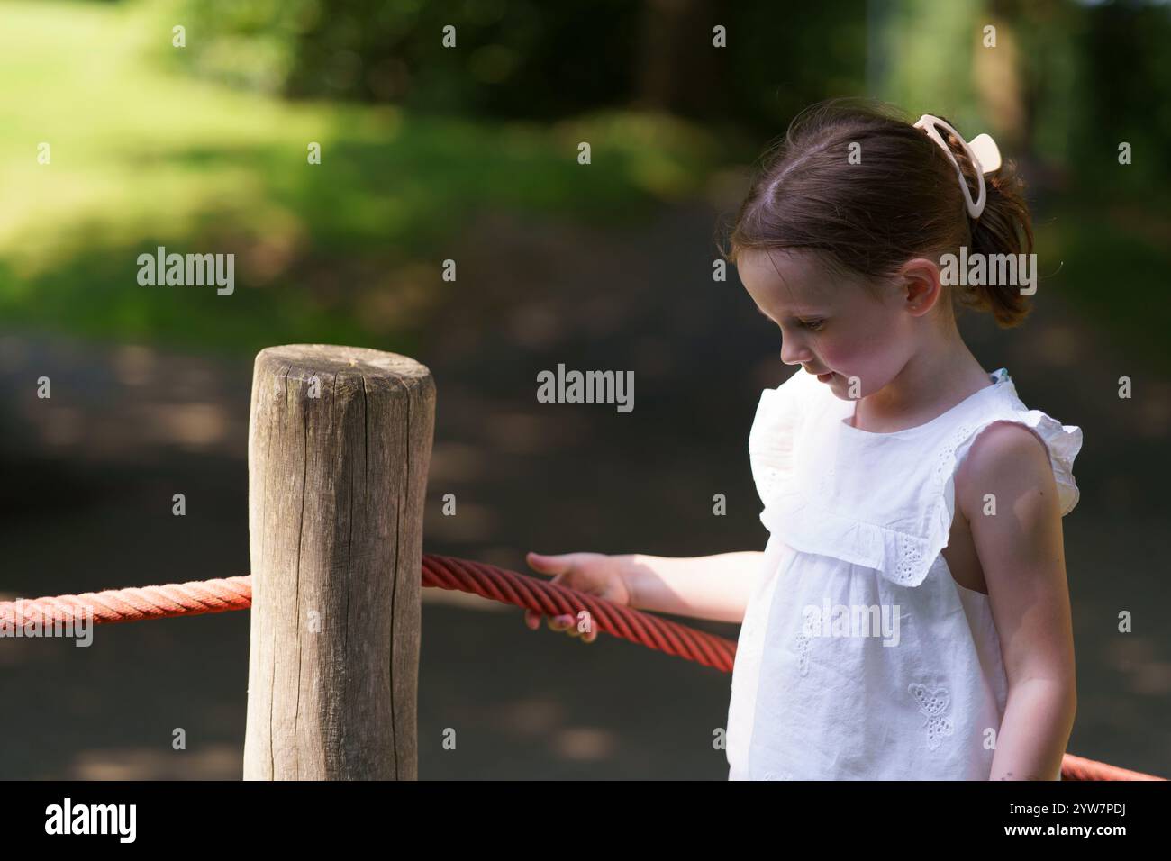 Little cute girl without front tooth rope playground summer park ...