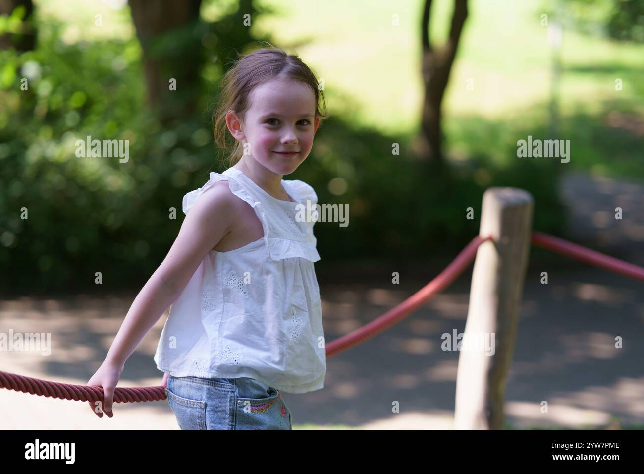 Little cute girl without front tooth rope playground summer park ...