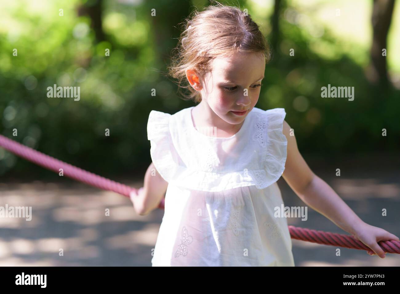 Little cute girl without front tooth rope playground summer park ...