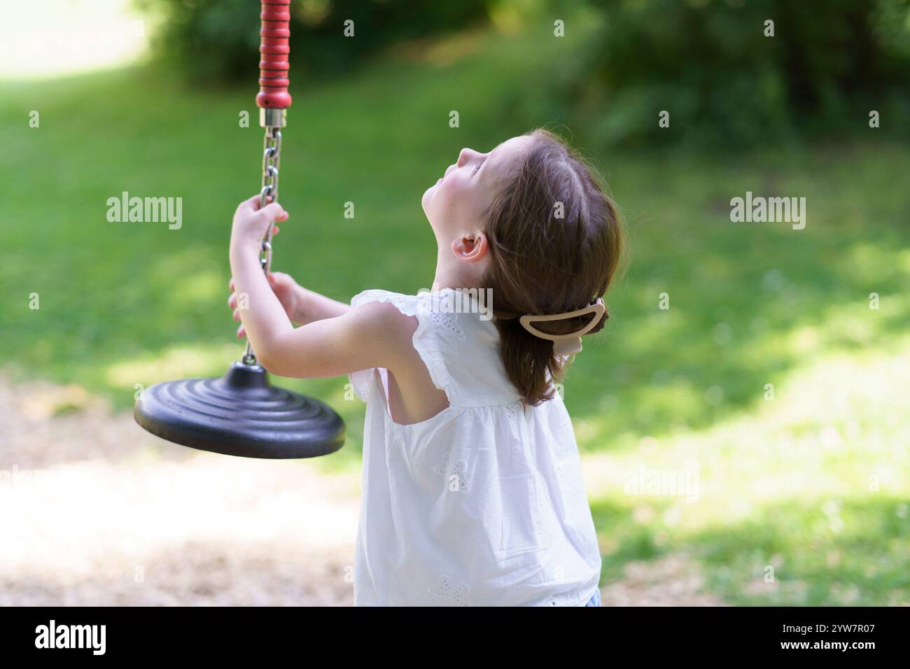Little cute girl without front tooth rides on a suspended slide in a ...