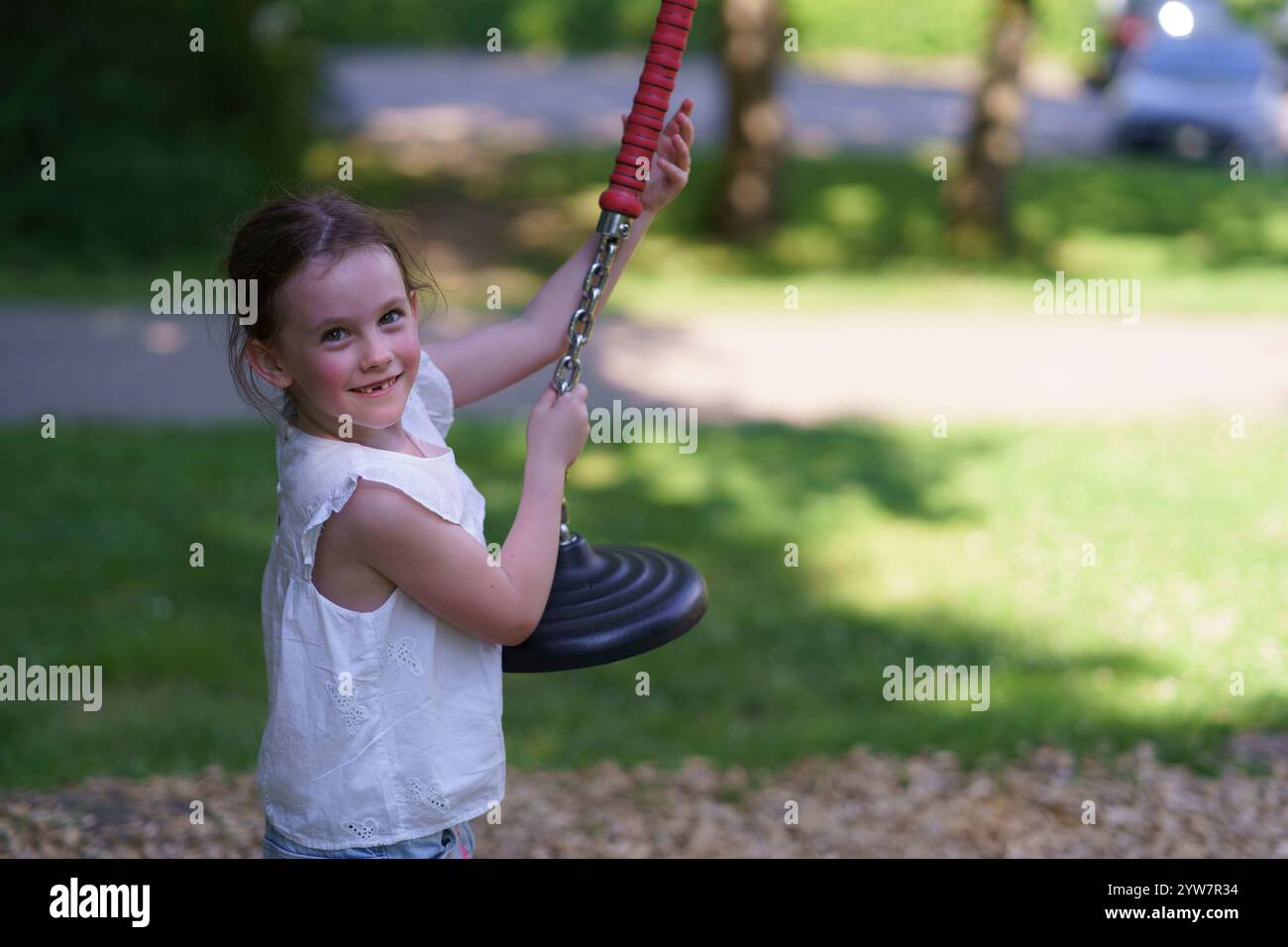 Little cute girl without front tooth rides on a suspended slide in a ...
