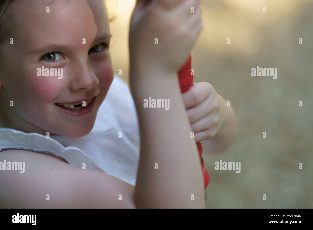Little cute girl without front tooth rides on a suspended slide in a ...
