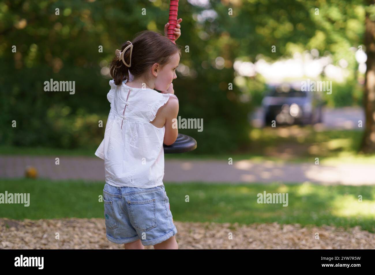 Little cute girl without front tooth rides on a suspended slide in a ...