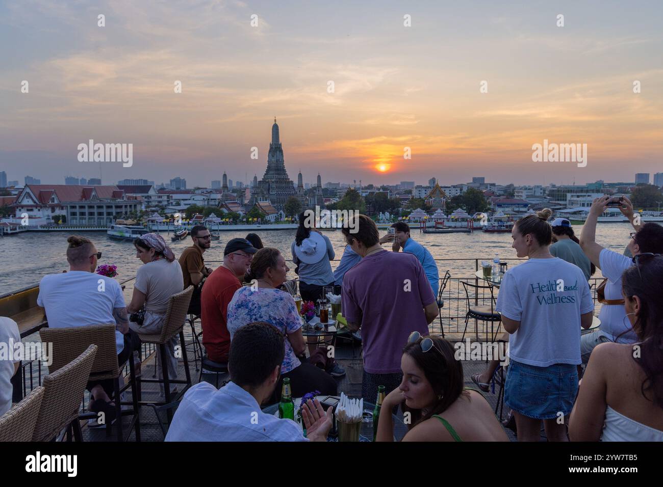 A rooftop bar at sunset with a view of the Chao Phraya River and Wat ...