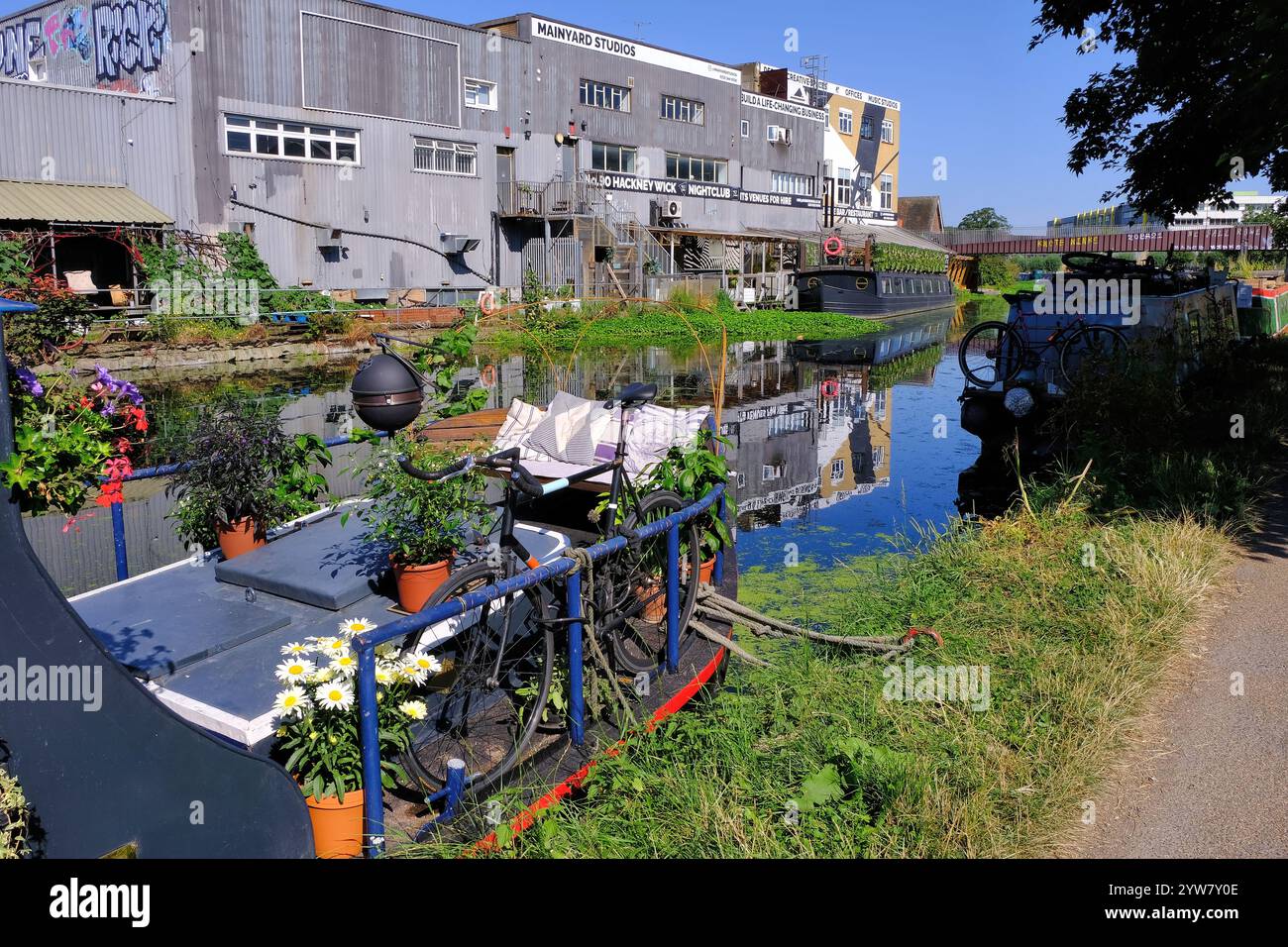 Colourful canal boats, barges, flowers, industrial buildings and bridge ...