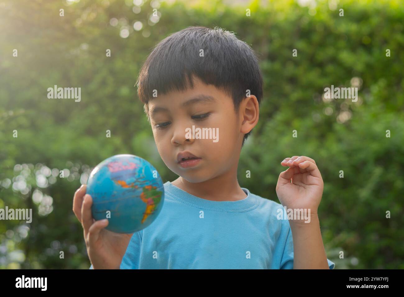 Portrait image of Asian child play earth planet ball toy over nature background. Earth Day ...