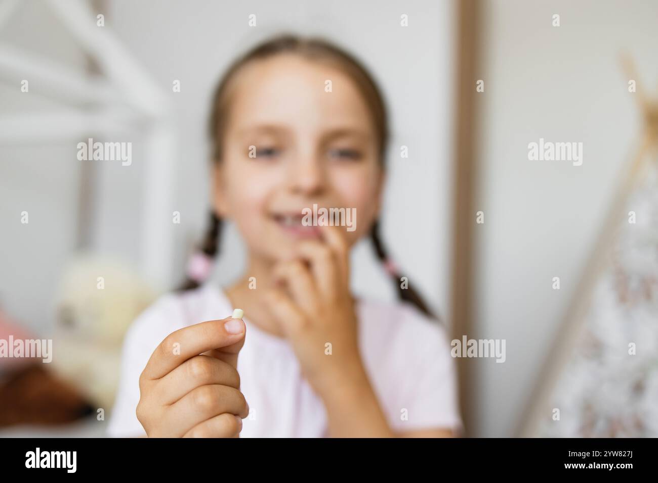 Little Caucasian girl proudly holding her fallen baby tooth indoors ...