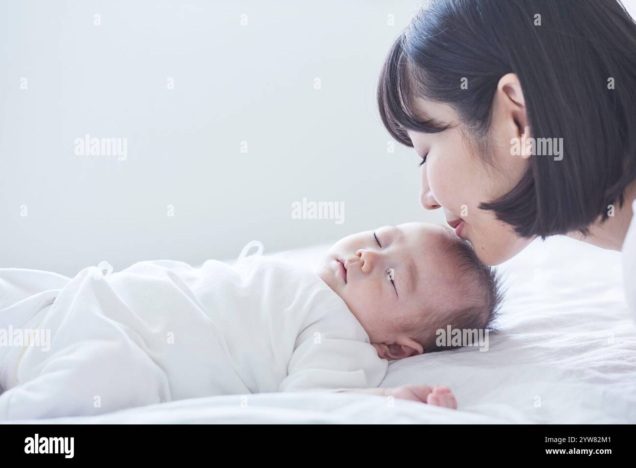 Happy mother watching over baby son in crib with father smiling at ...