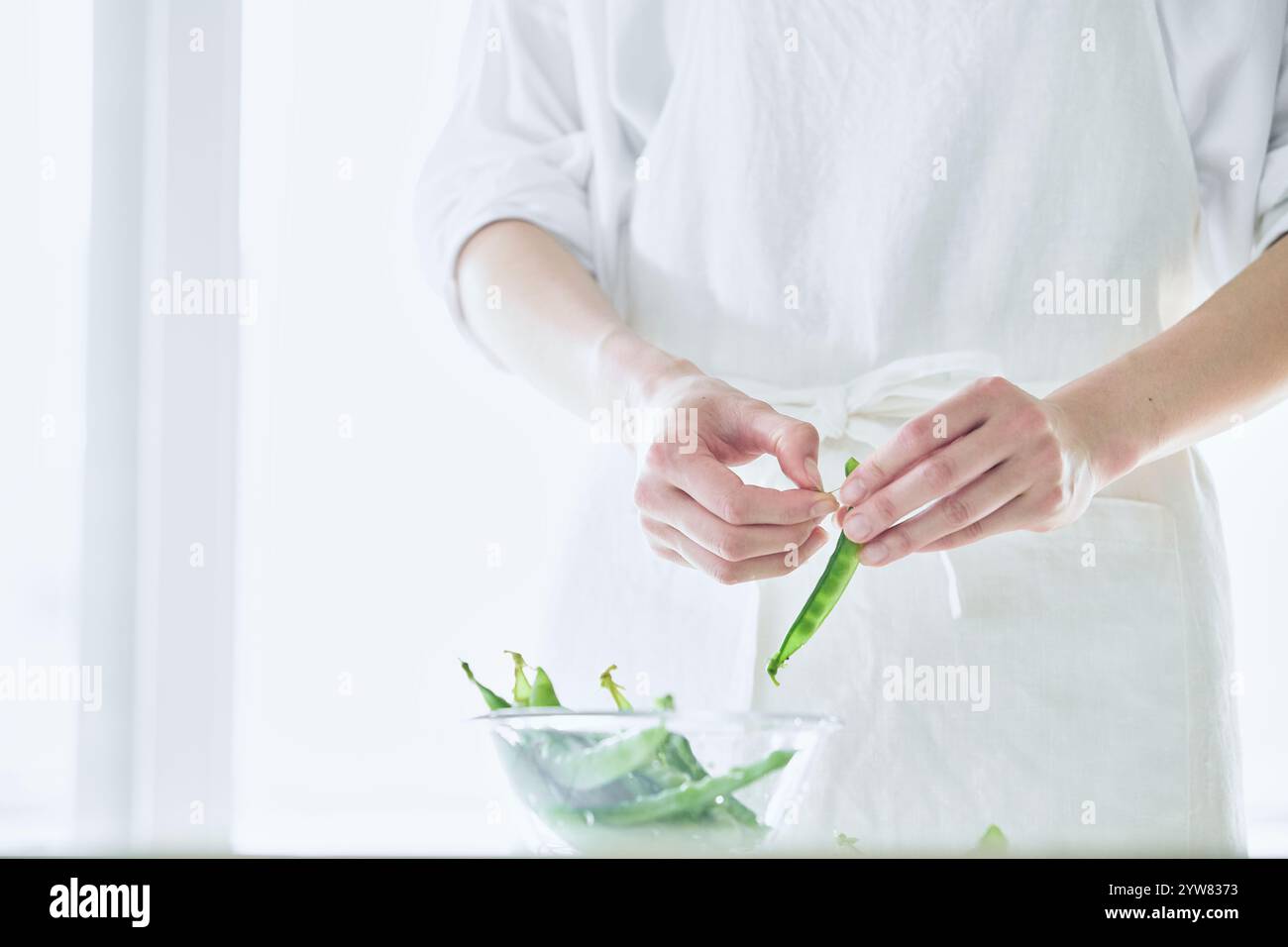 Woman removing threads from a pod of peas Stock Photo - Alamy