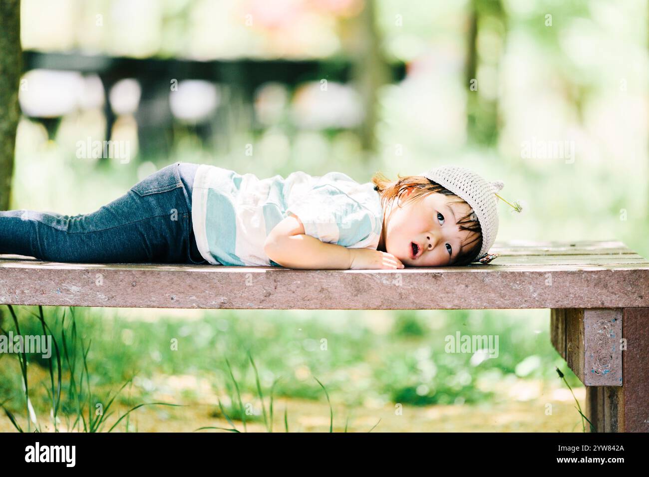 Girl lying on bench in shade of tree Stock Photo - Alamy