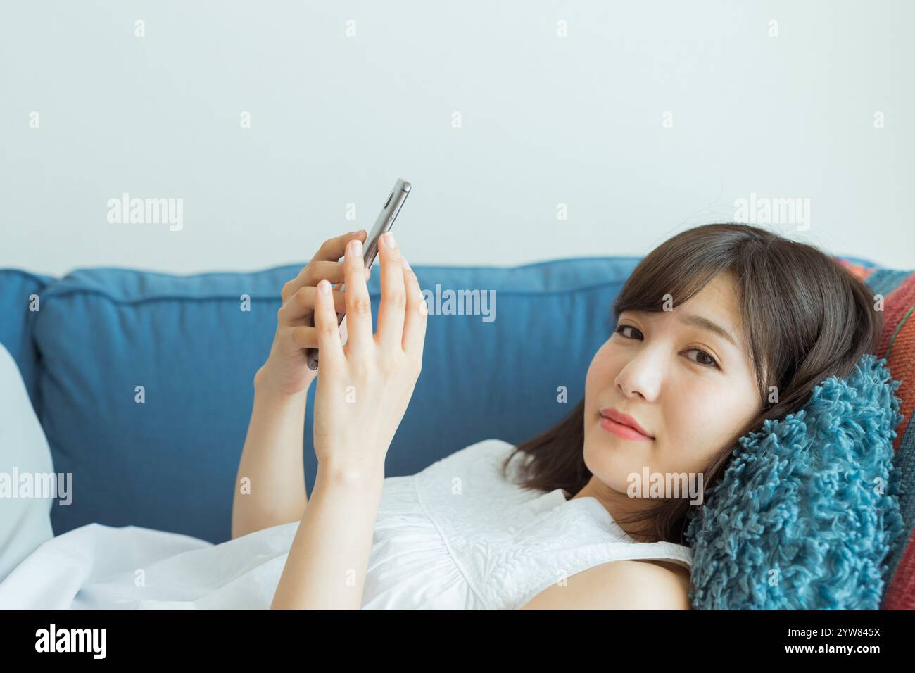 Woman operating a smartphone lying down Stock Photo - Alamy