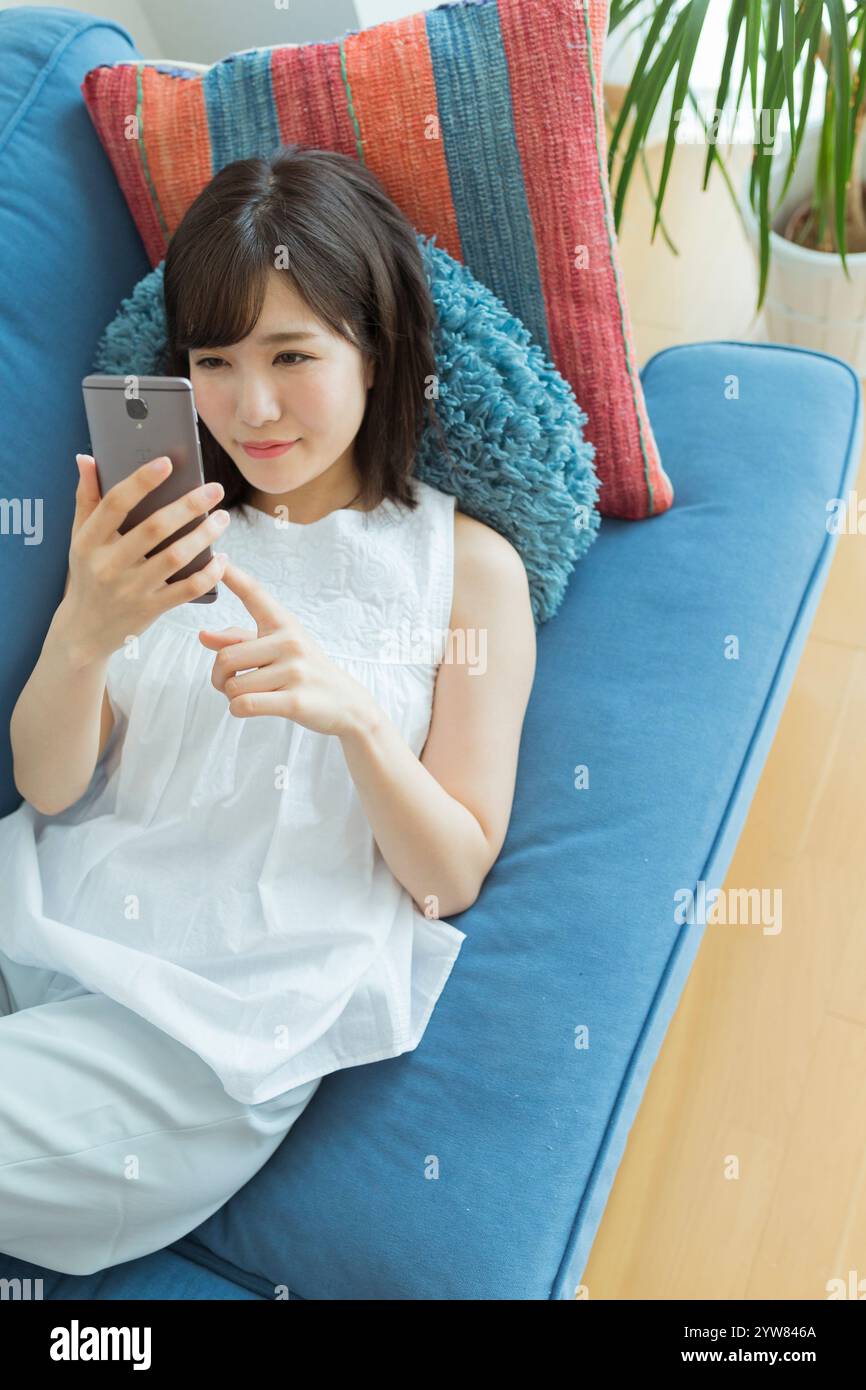 Woman operating a smartphone lying down Stock Photo - Alamy
