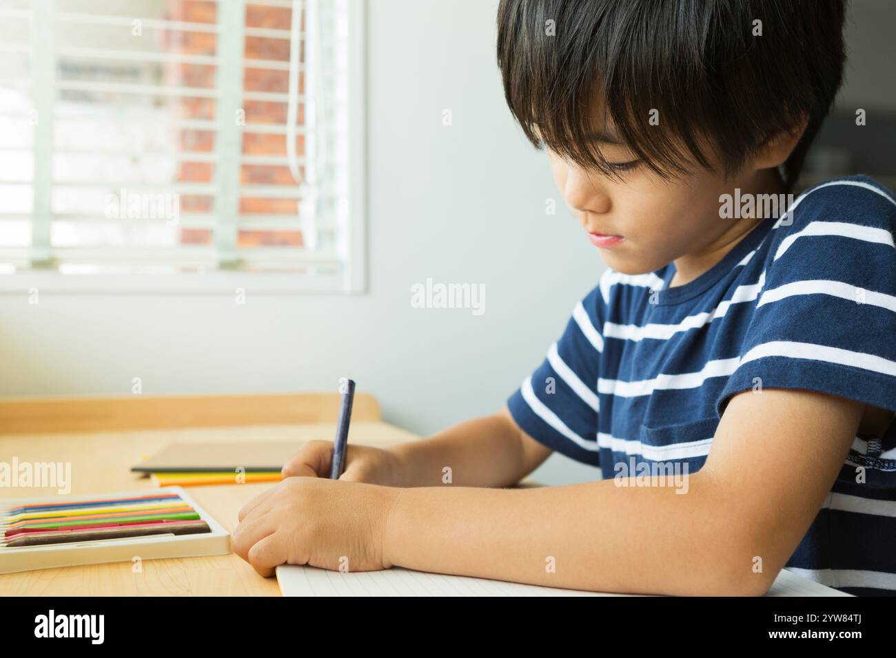 Primary school boy drawing a picture in profile Stock Photo - Alamy