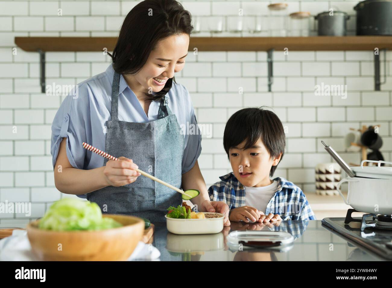 Boy cuddling with woman making lunch in kitchen Stock Photo - Alamy