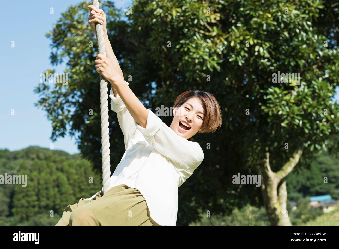 Woman in her 20s playing on Tarzan rope Stock Photo - Alamy