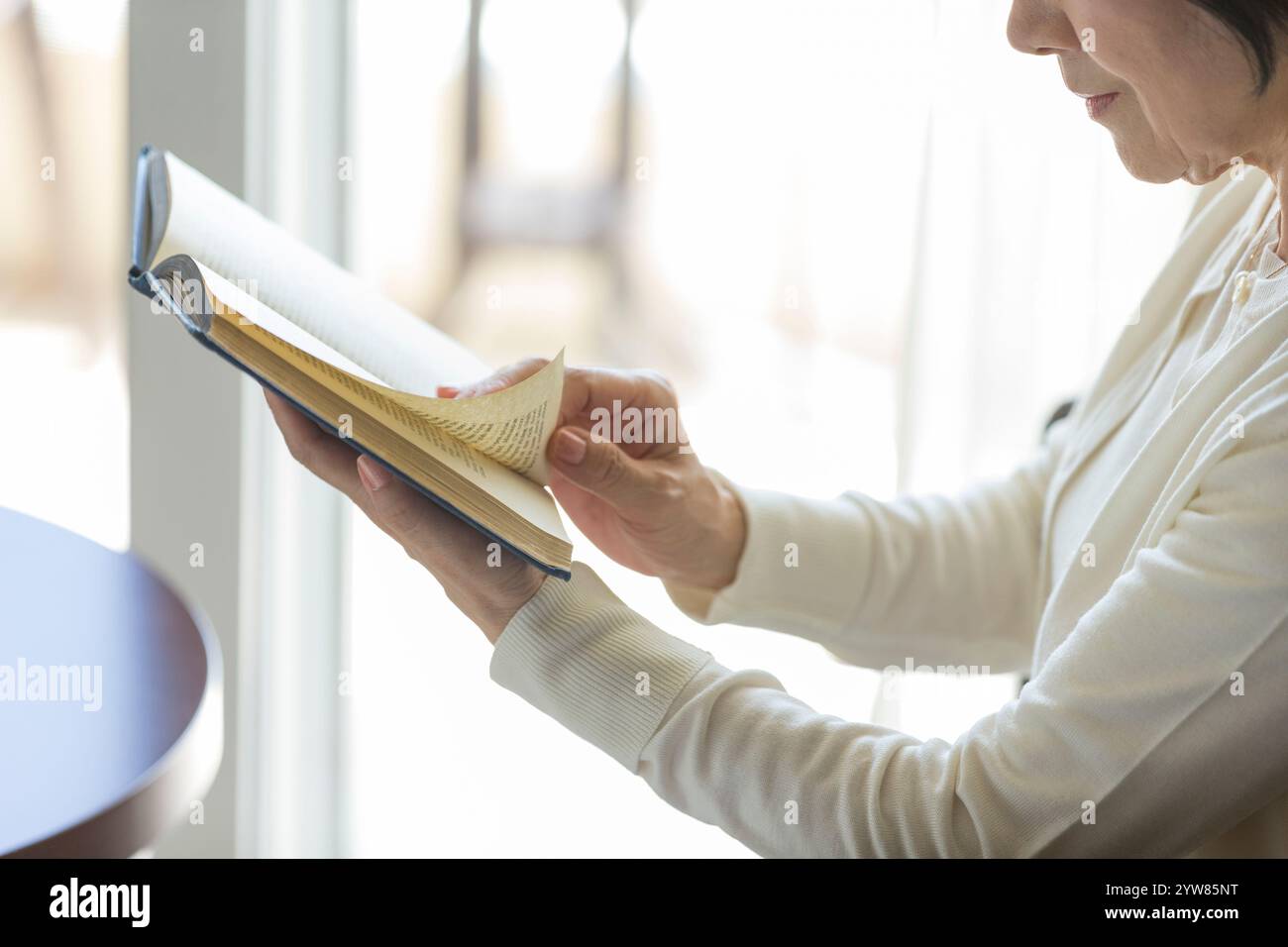 Senior woman's hand turning pages of a book Stock Photo - Alamy