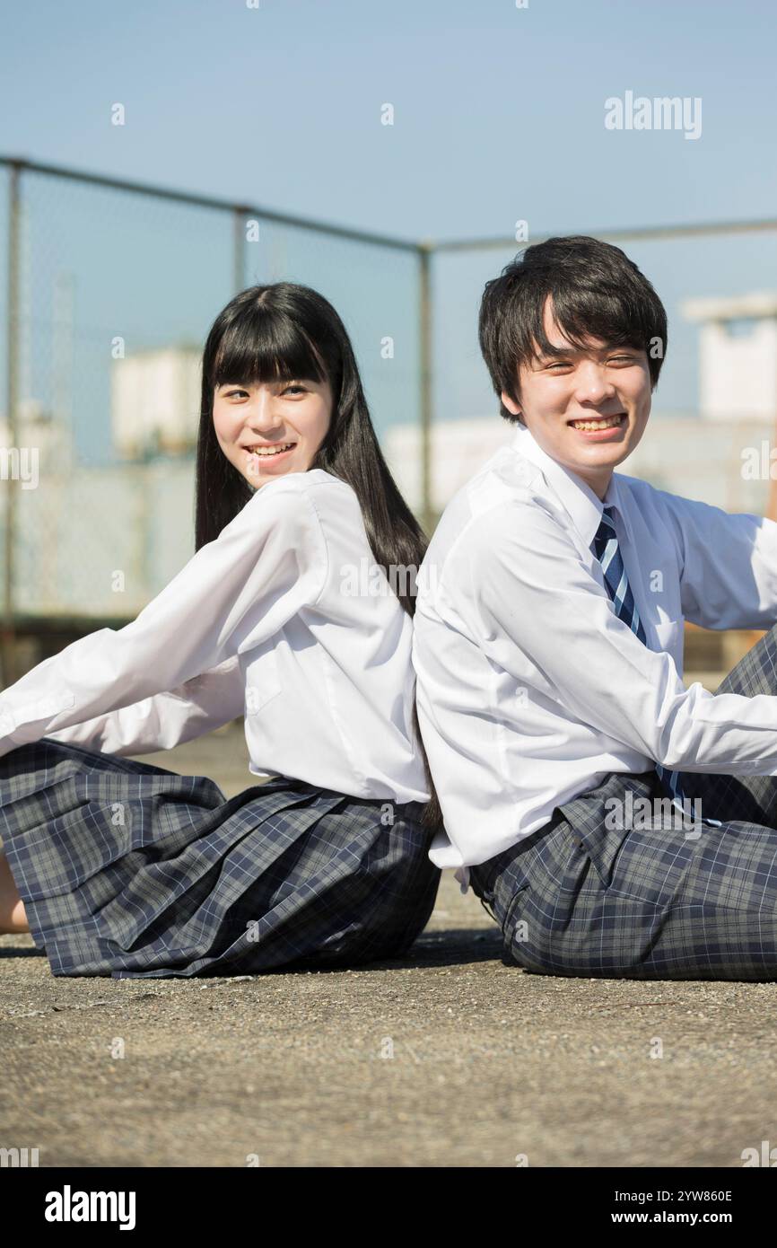 Portraits of female and male high school students sitting back-to-back ...