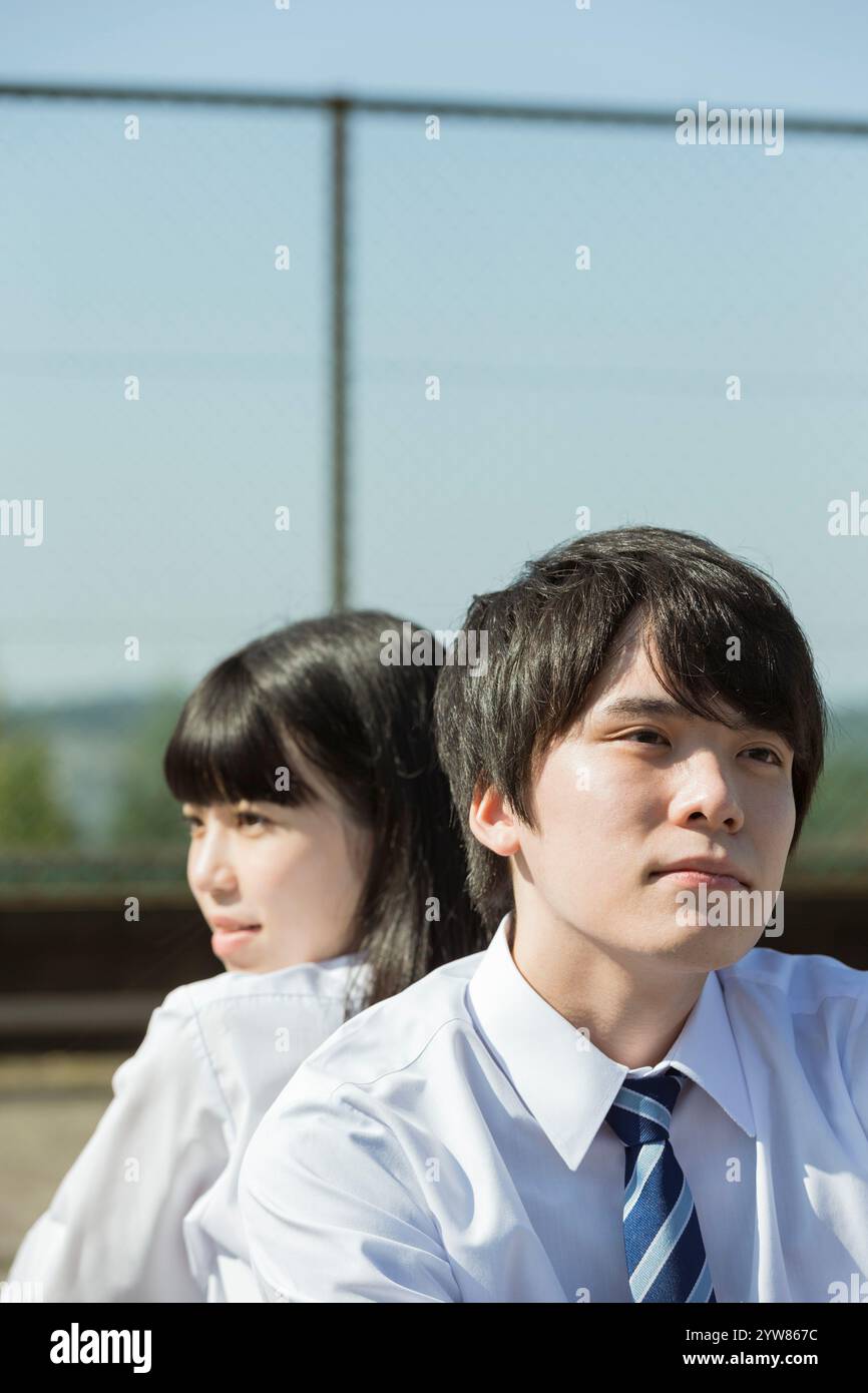 Female and male high school students sitting back-to-back Stock Photo ...