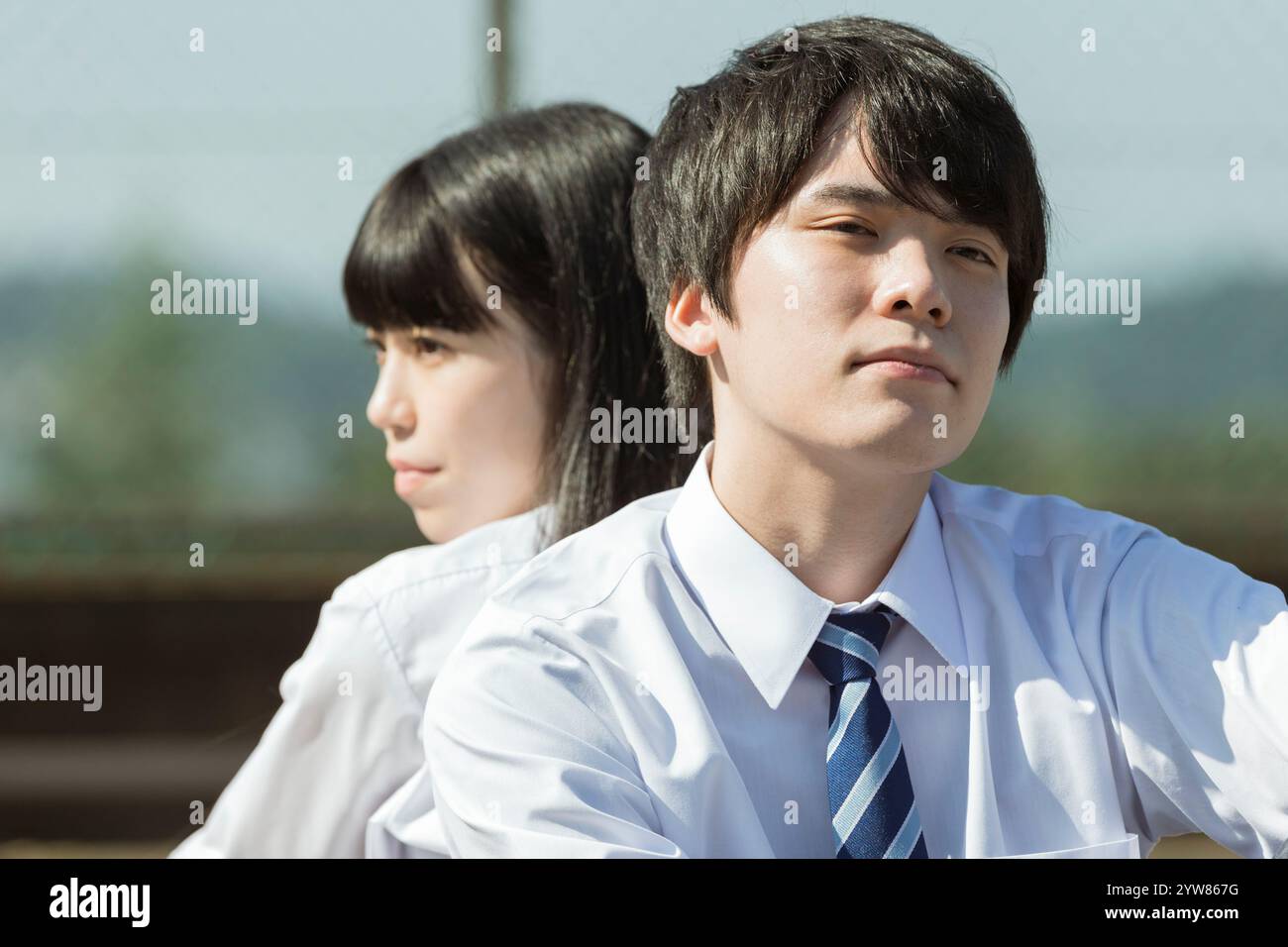 Female and male high school students sitting back-to-back Stock Photo ...