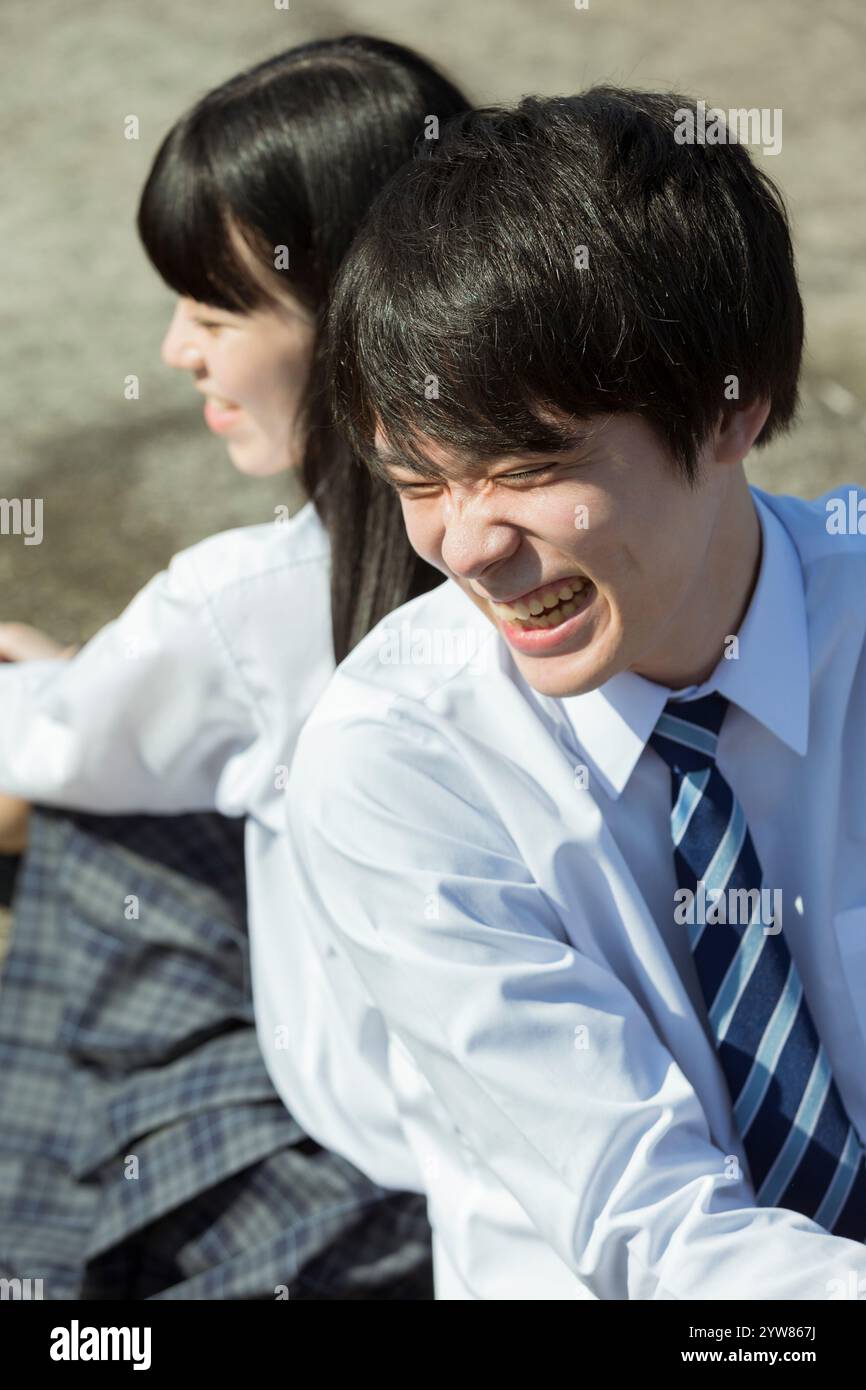 Female and male high school students sitting back-to-back Stock Photo ...