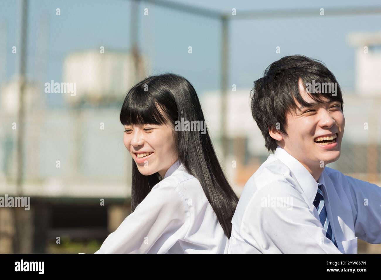 Female and male high school students sitting back-to-back Stock Photo ...