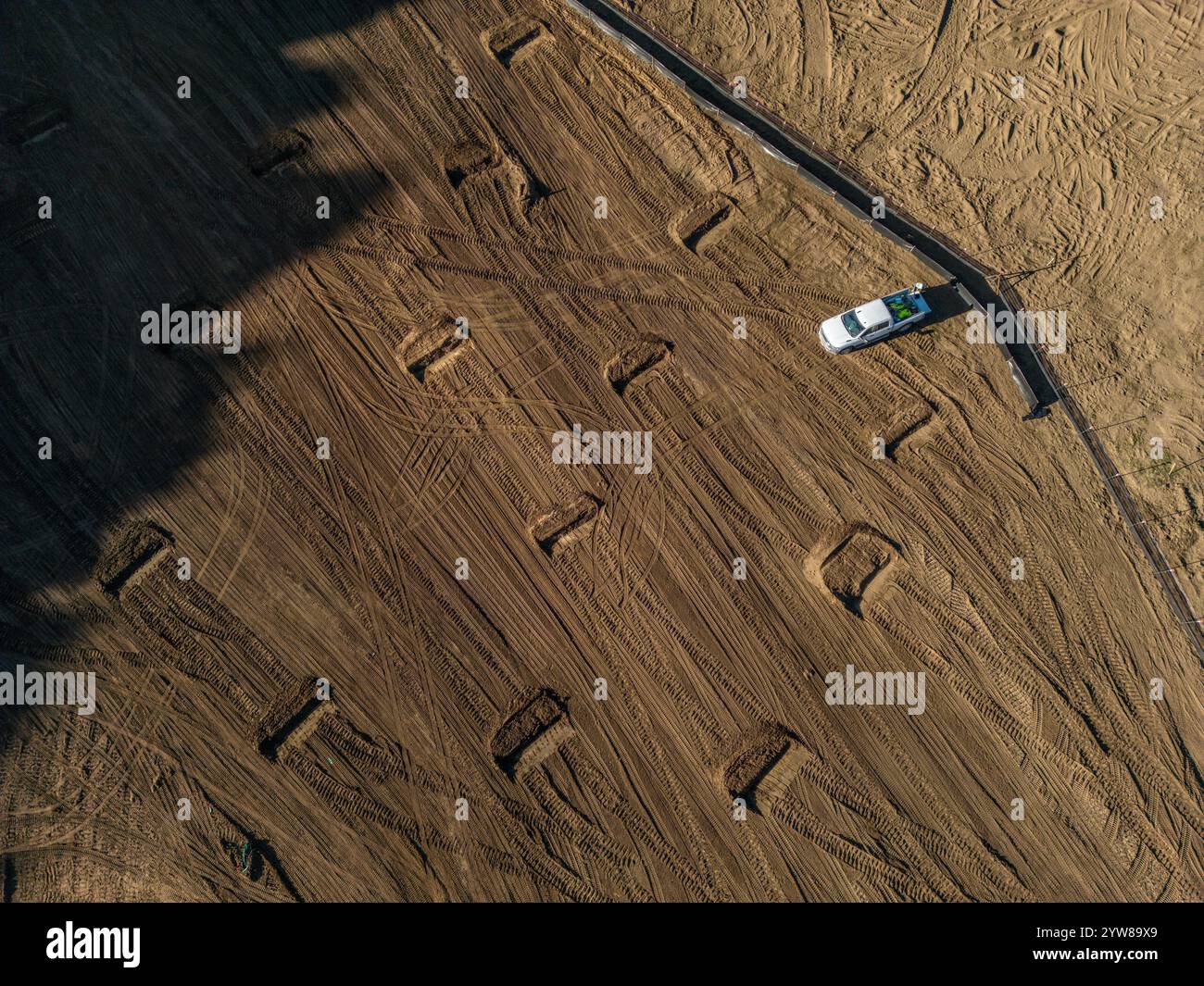 A parked truck, tire tracks through the dusty soil on a construction ...