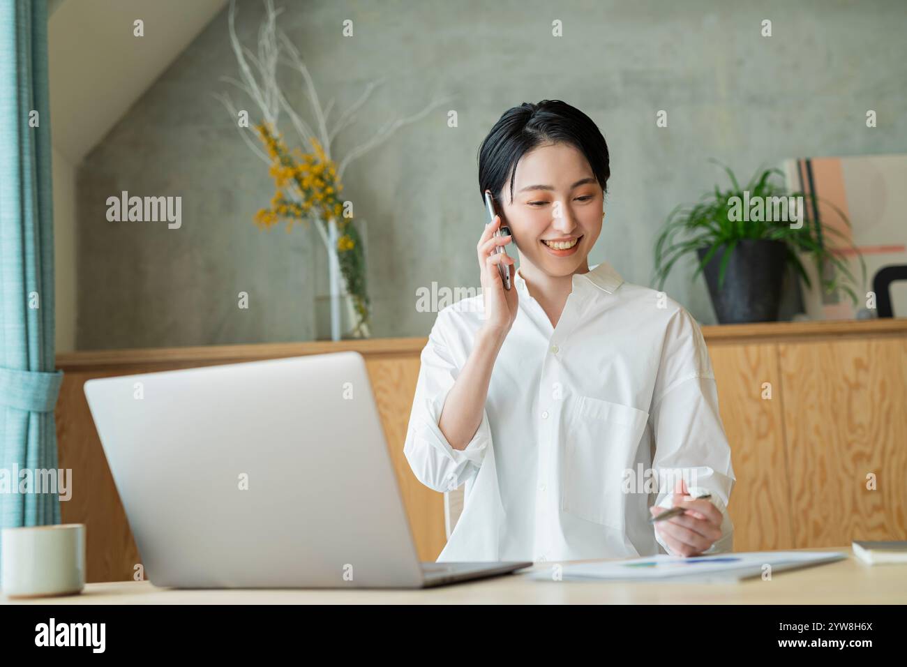 Woman taking a phone call while working remotely Stock Photo - Alamy