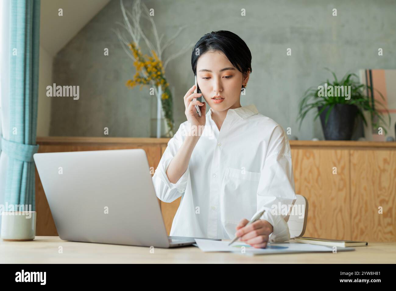 Woman taking a phone call while working remotely Stock Photo - Alamy