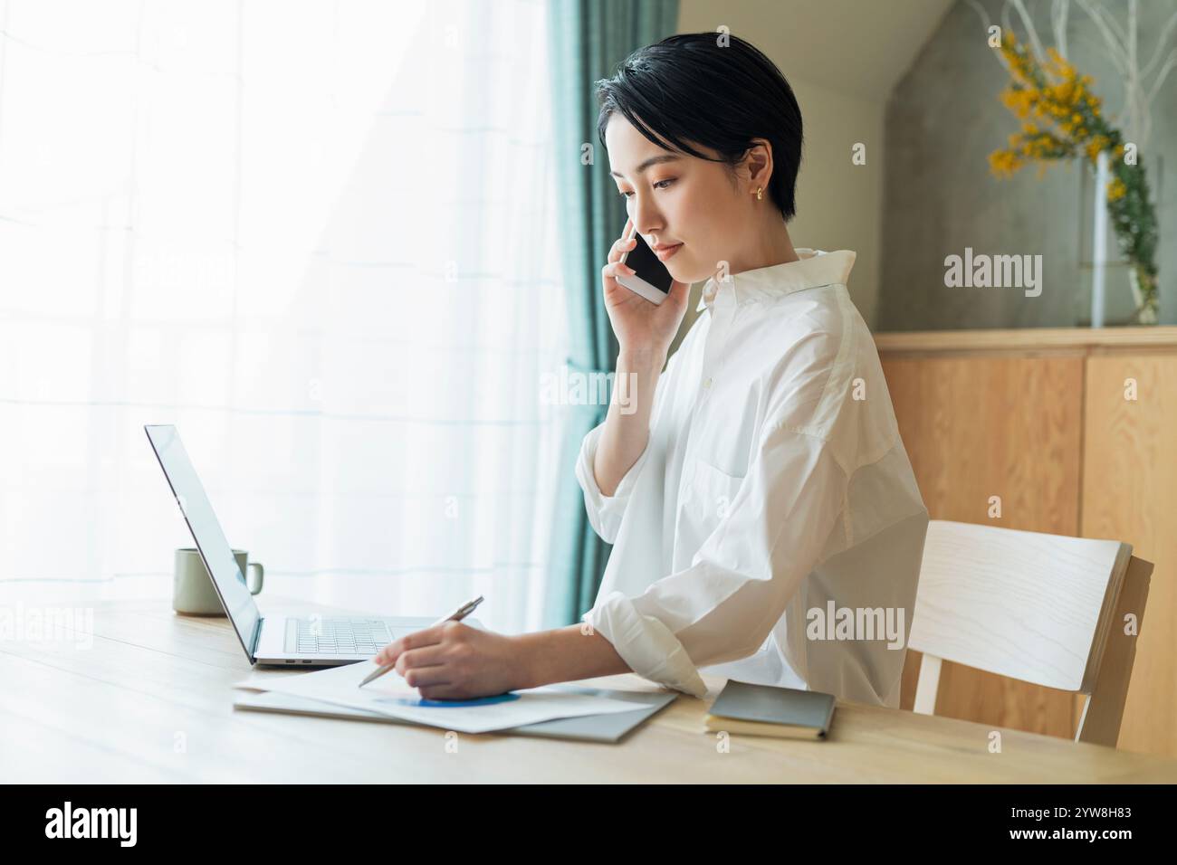 Woman taking a phone call while working remotely Stock Photo - Alamy