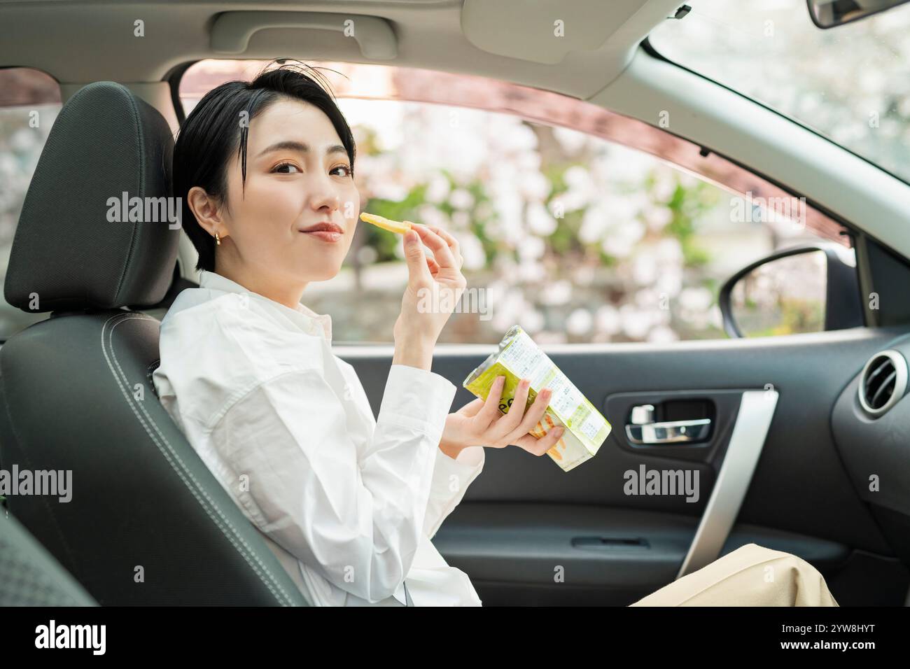 Woman eating sweets while driving Stock Photo - Alamy