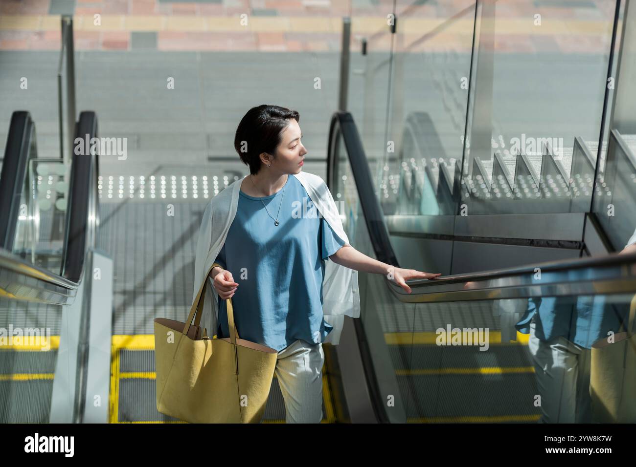 Woman riding escalator Stock Photo - Alamy